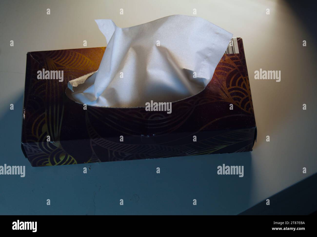 A photo of a rectangular tissue box for colds and flus on a white desk ...