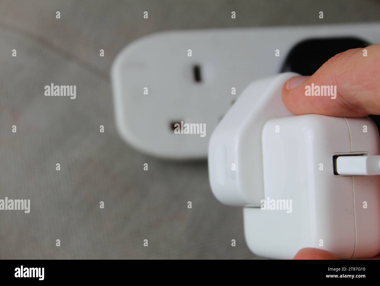 A photo of someone plugging in an electrical smartphone charger plug ...