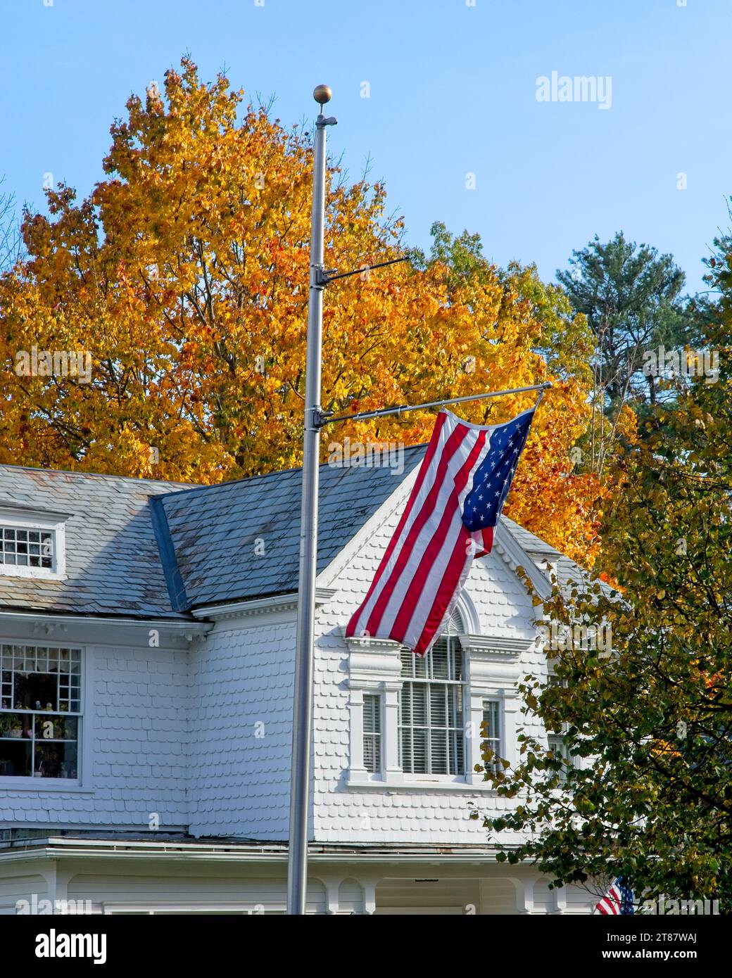 Vibrant foliage, American flag around white New England home upper ...