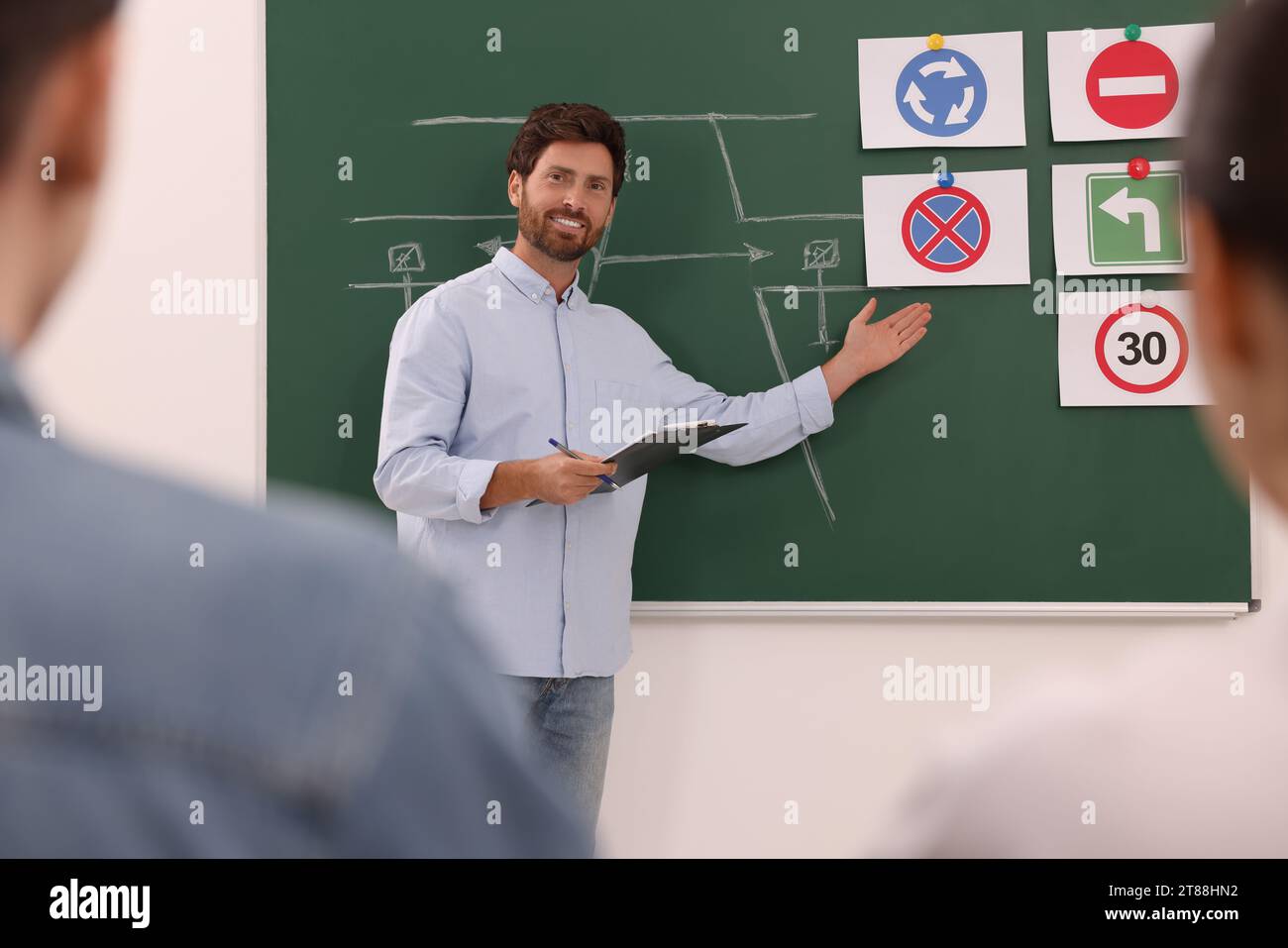 Teacher explaining traffic rules to audience during lesson in driving ...
