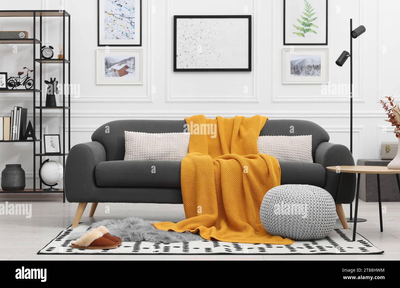 Stylish living room interior with comfortable sofa, blanket, side table ...
