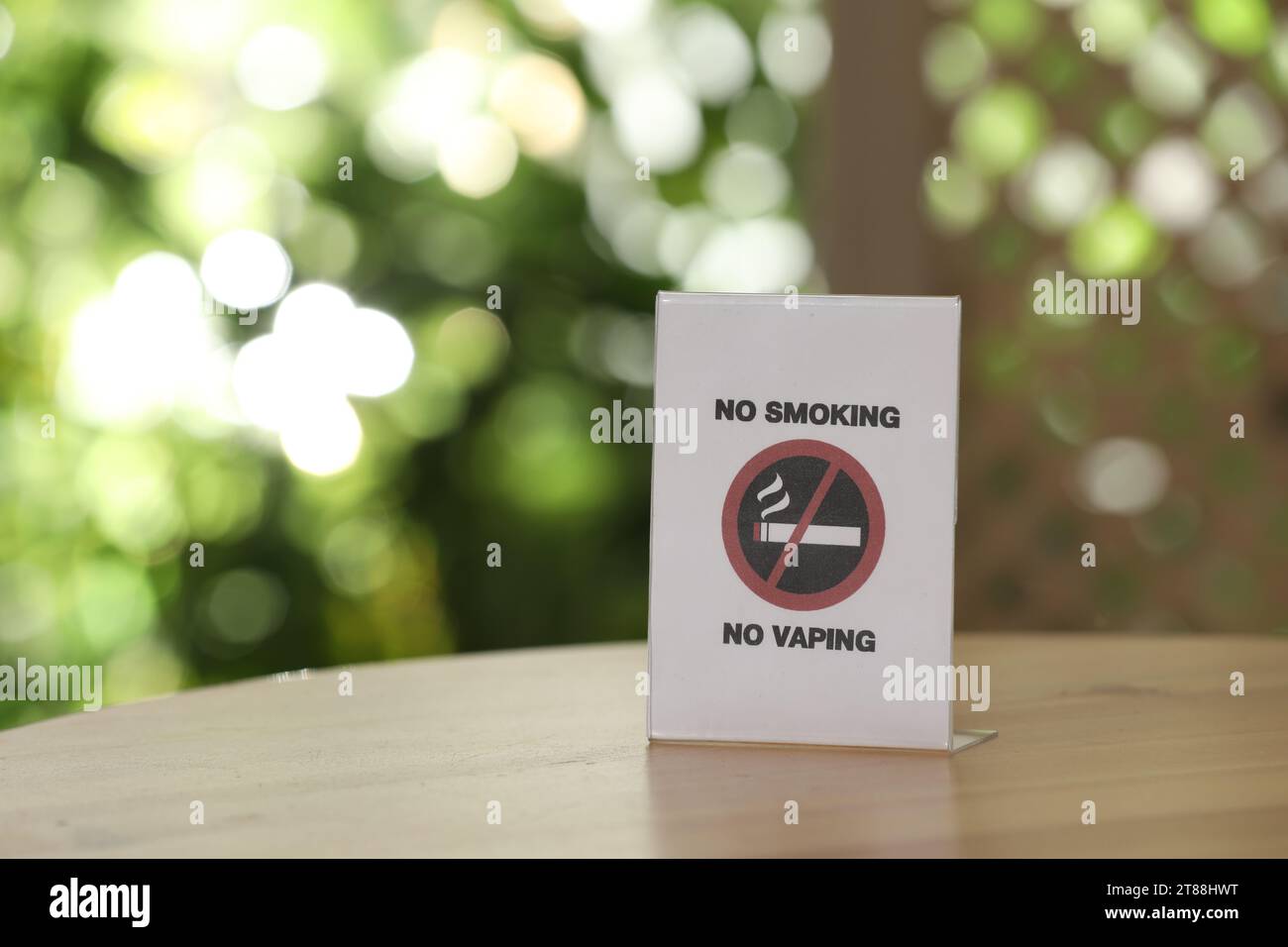 No Smoking No Vaping sign on wooden table against blurred background ...