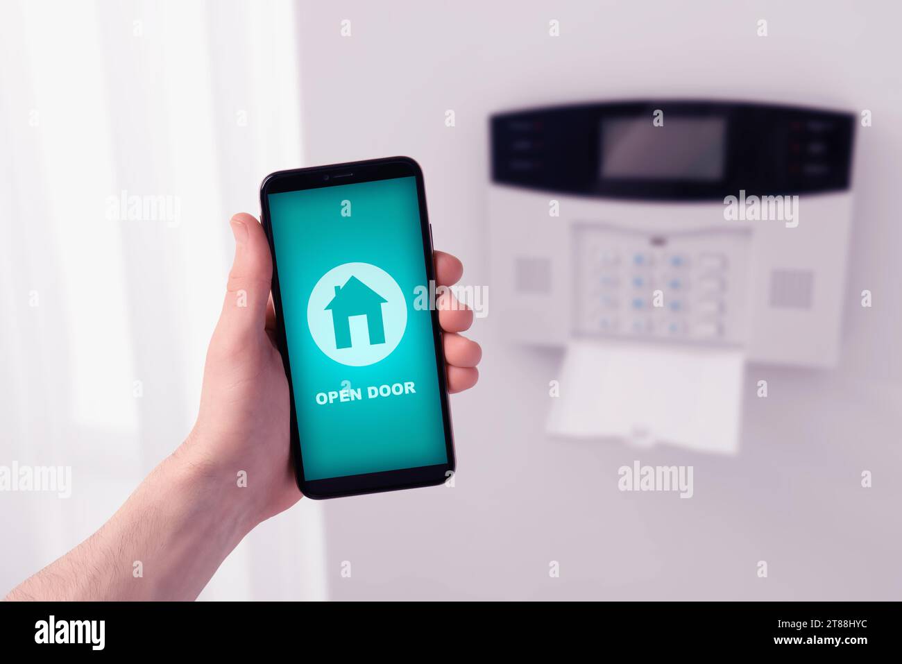 Man operating home alarm system via mobile phone against white wall ...