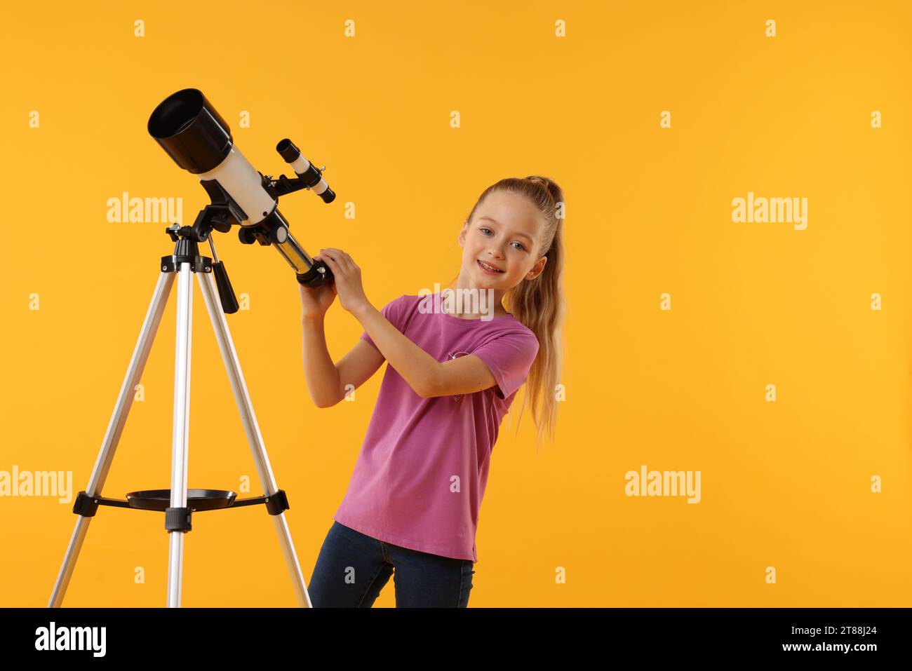 Happy little girl with telescope on orange background, space for text ...