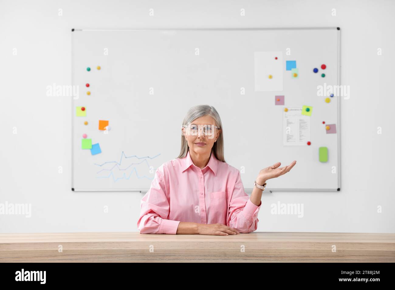 Professor giving lecture at desk in classroom Stock Photo - Alamy