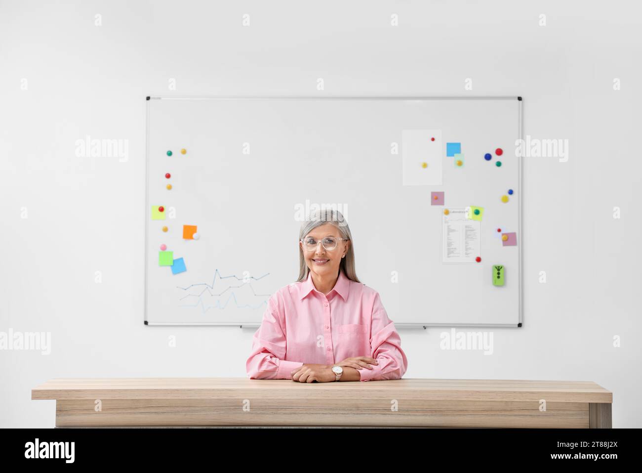 Portrait of professor sitting at desk in classroom Stock Photo - Alamy