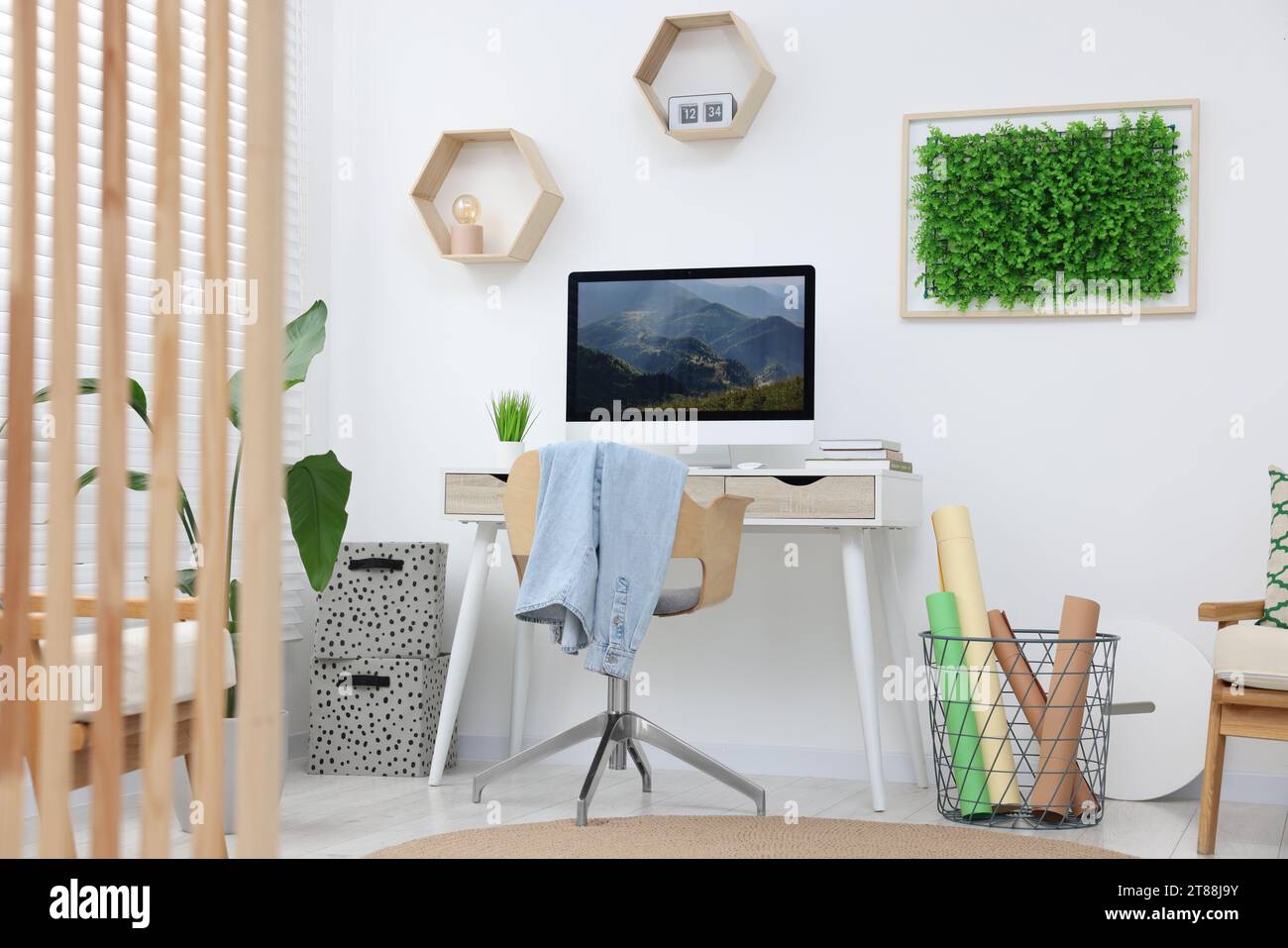 Green artificial plant wall panel and desk with computer in light room ...