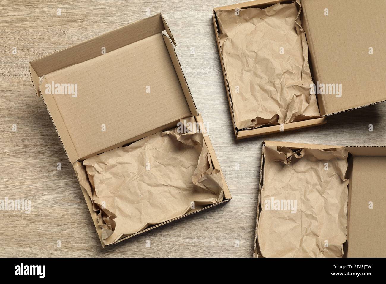 Open cardboard boxes with crumpled paper on wooden background, flat lay ...