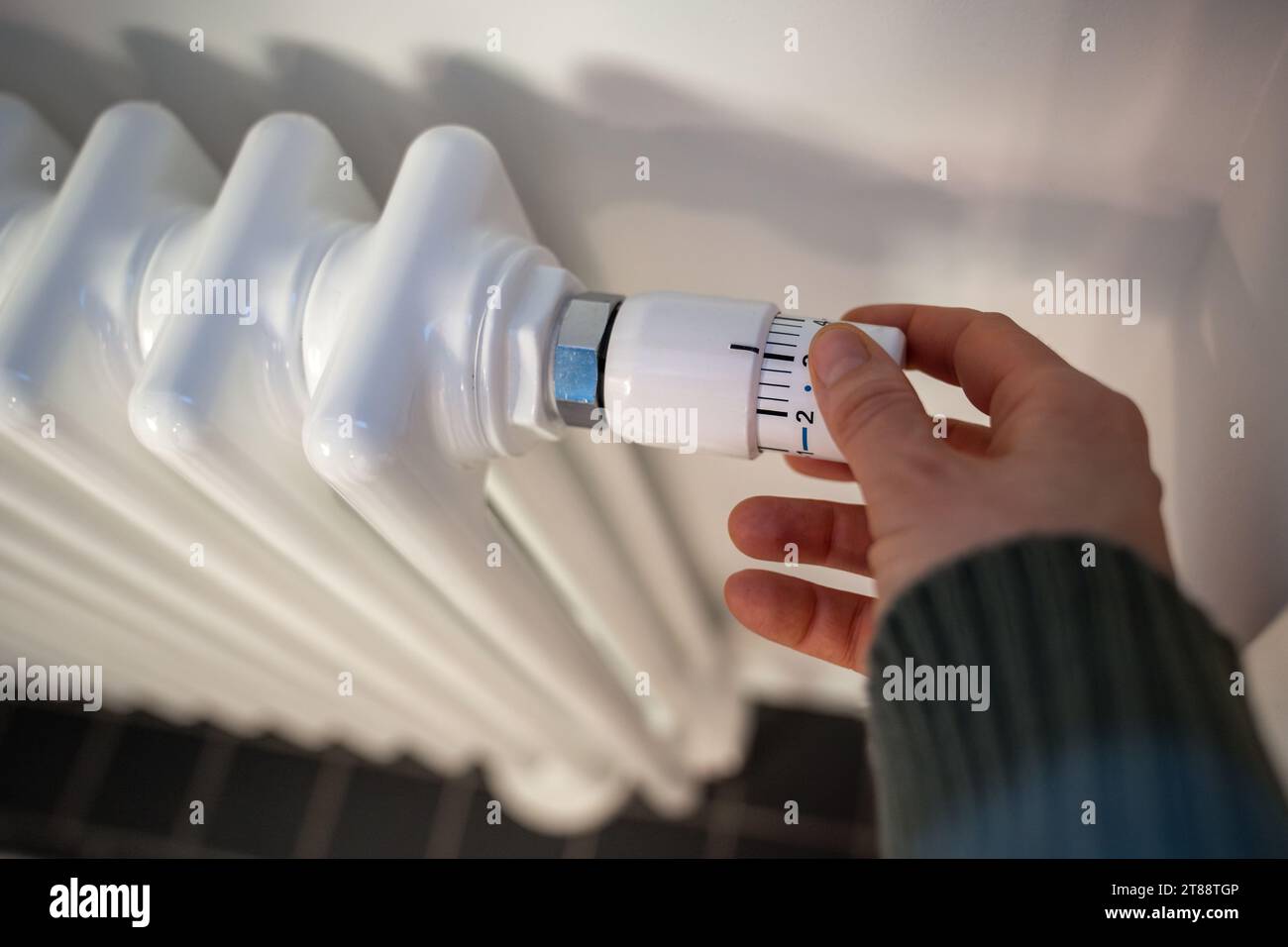 Hands adjusting radiator regulator, increasing temperature in house ...