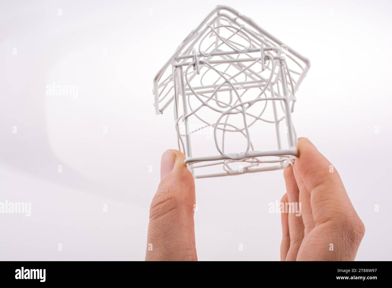 Little model house made of white metal wire in hand Stock Photo - Alamy