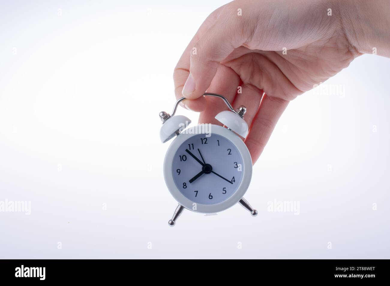 Alarm clock in hand on a white background Stock Photo - Alamy