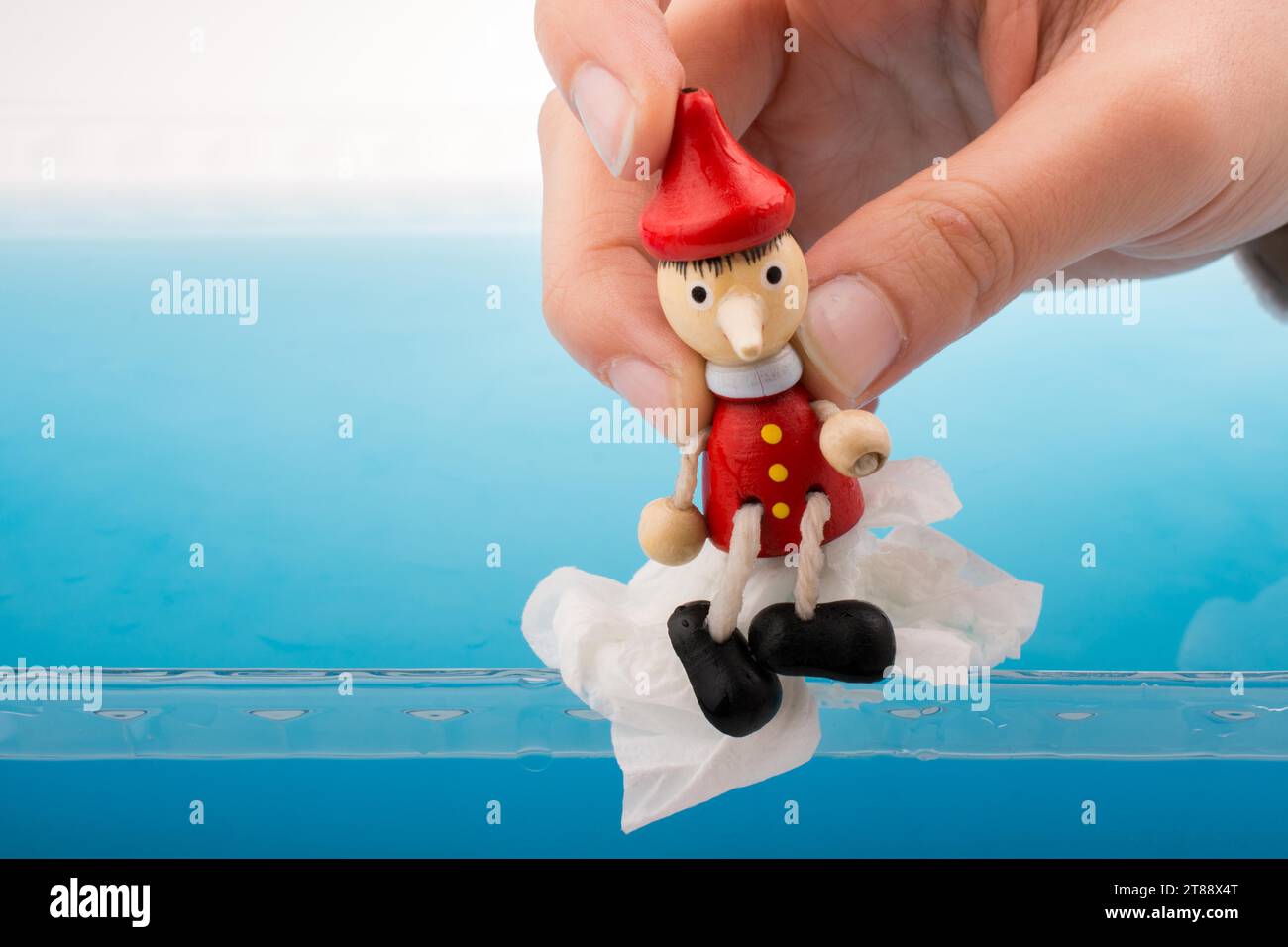 Hand holding wodden puppet Pinocchio on in blue water Stock Photo - Alamy