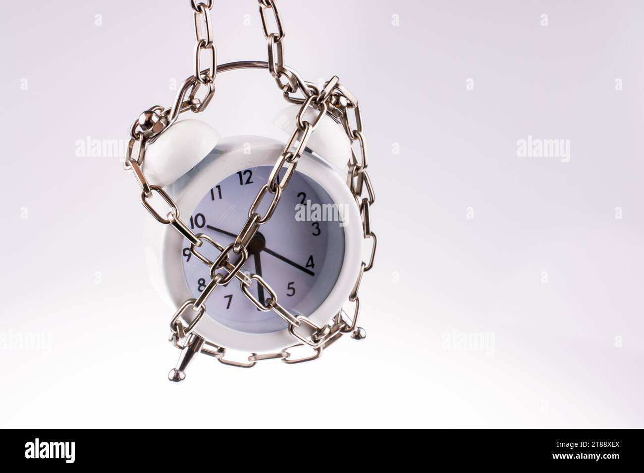 White color alarm clock in chain on a white background Stock Photo - Alamy