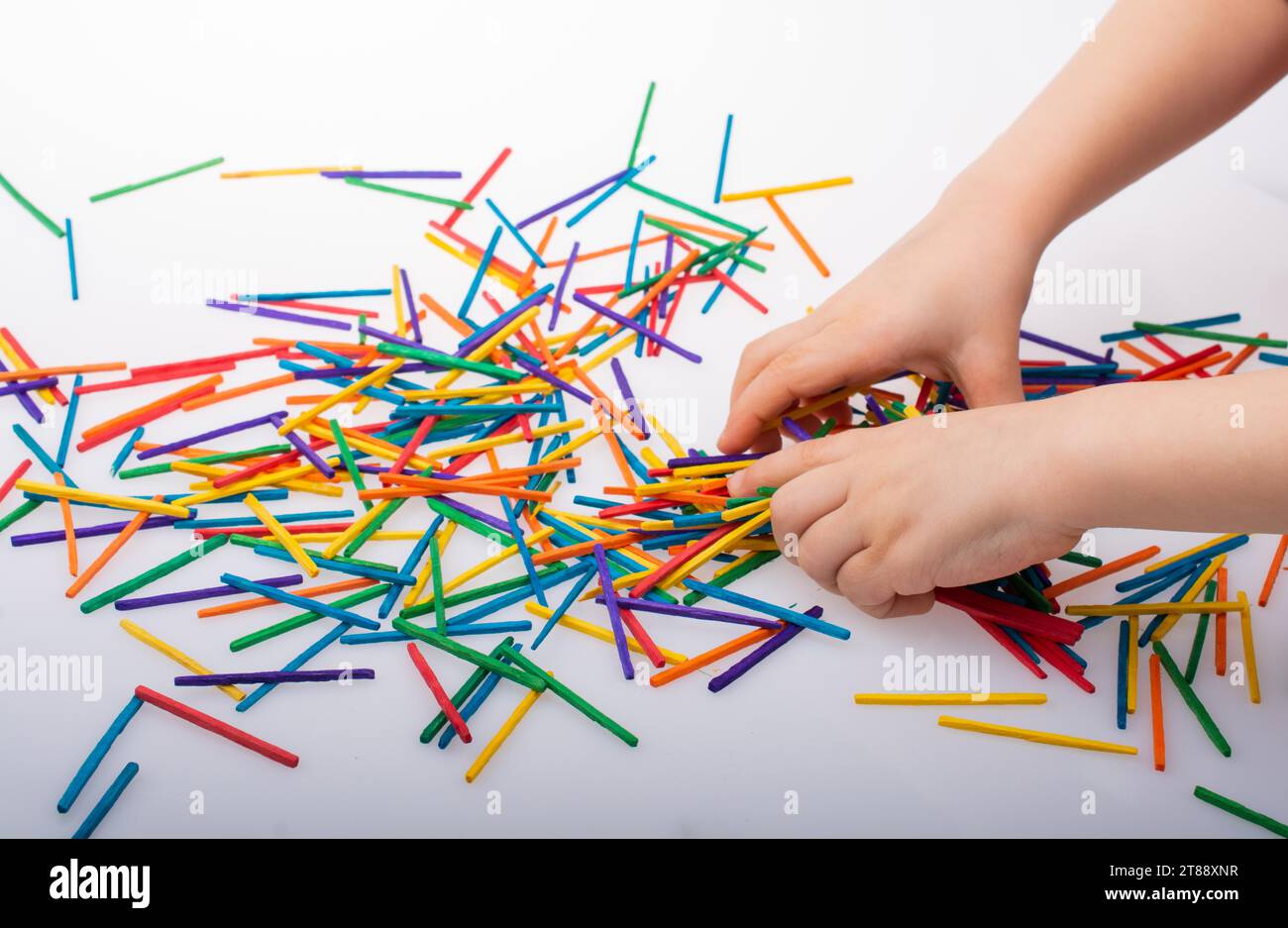 Hand letting coloured wooden sticks fall on white background Stock ...