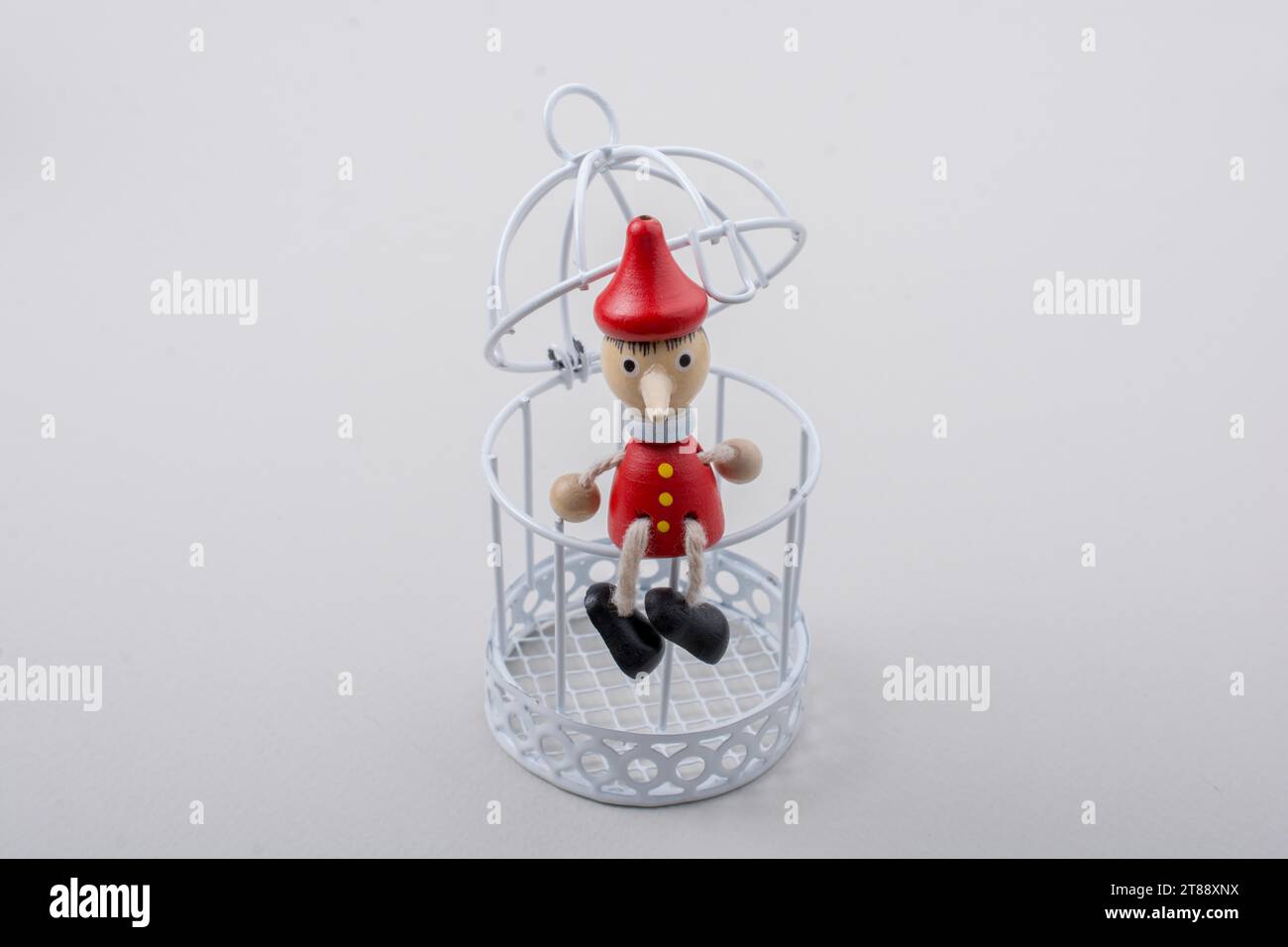 Metal cage and Little puppet pinocchio made of wood Stock Photo - Alamy