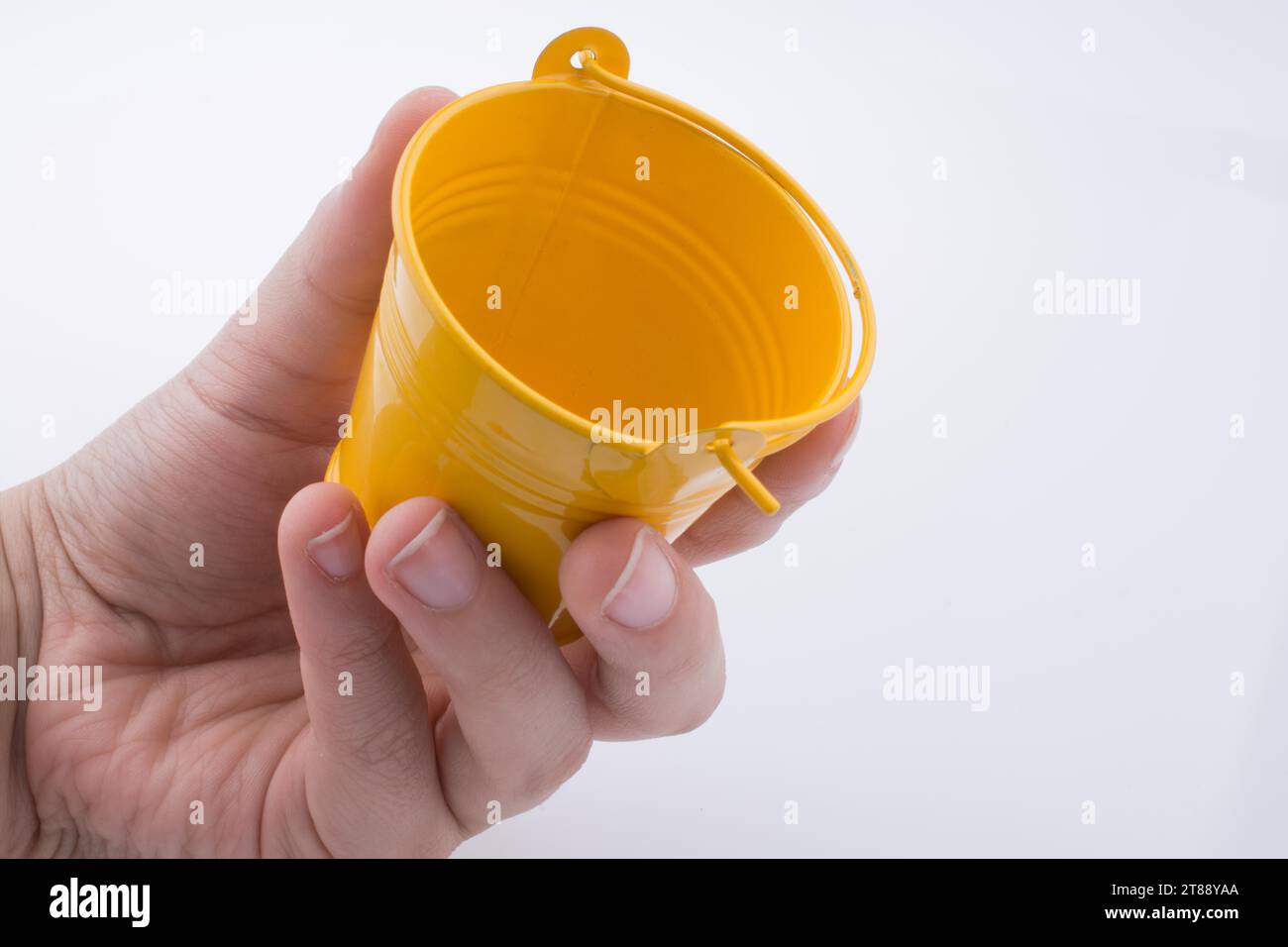 Hand holding a yellow bucket on a white background Stock Photo - Alamy