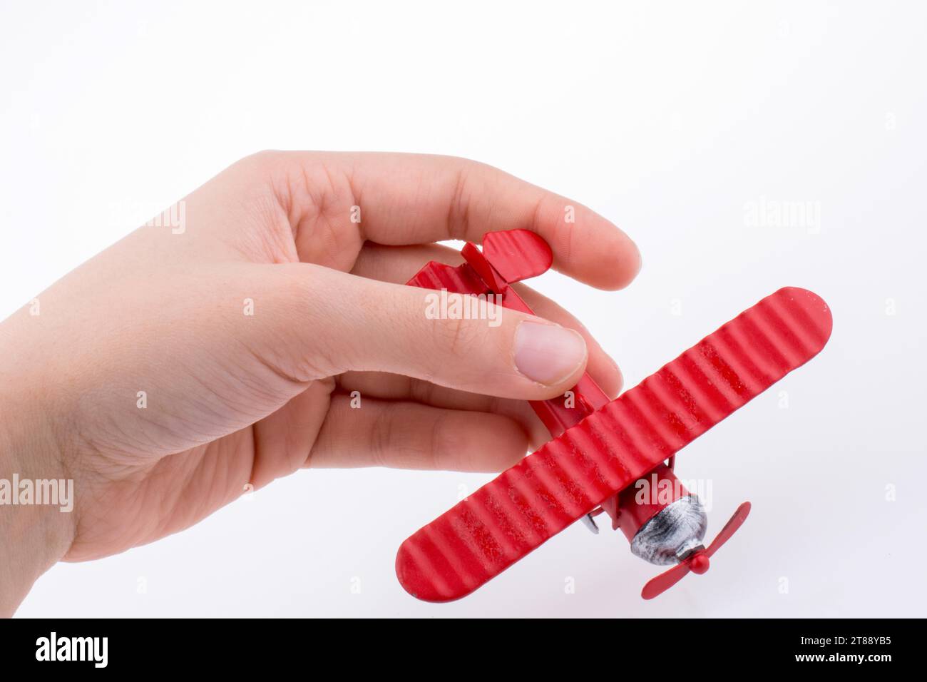 Hand holding a red toy plane on a white background Stock Photo - Alamy