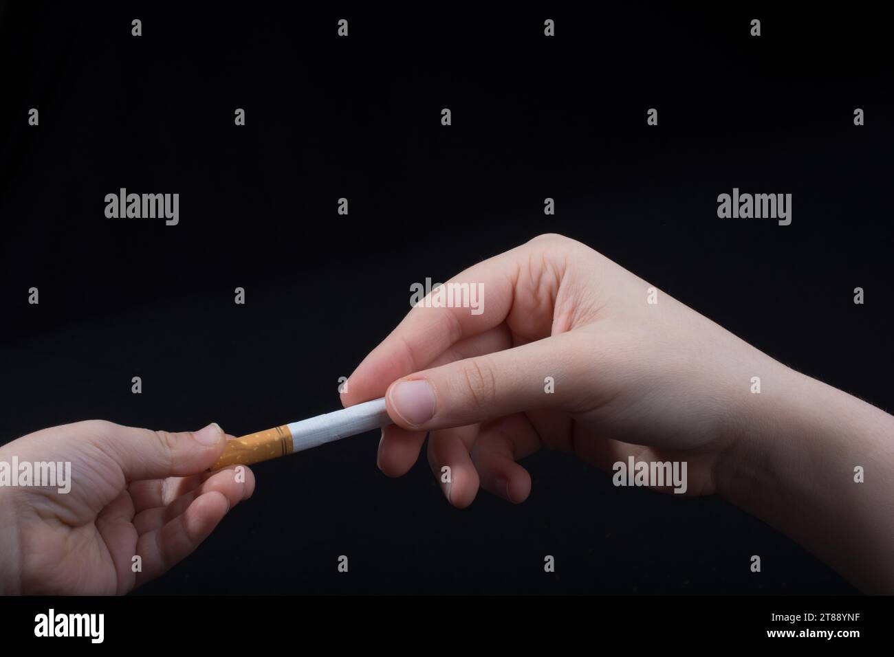Hand is giving out cigarette on a black background Stock Photo - Alamy