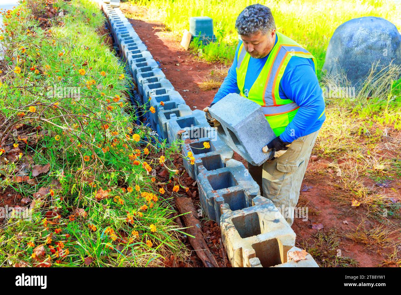 An employee of construction company mounts concrete blocks to retaining ...