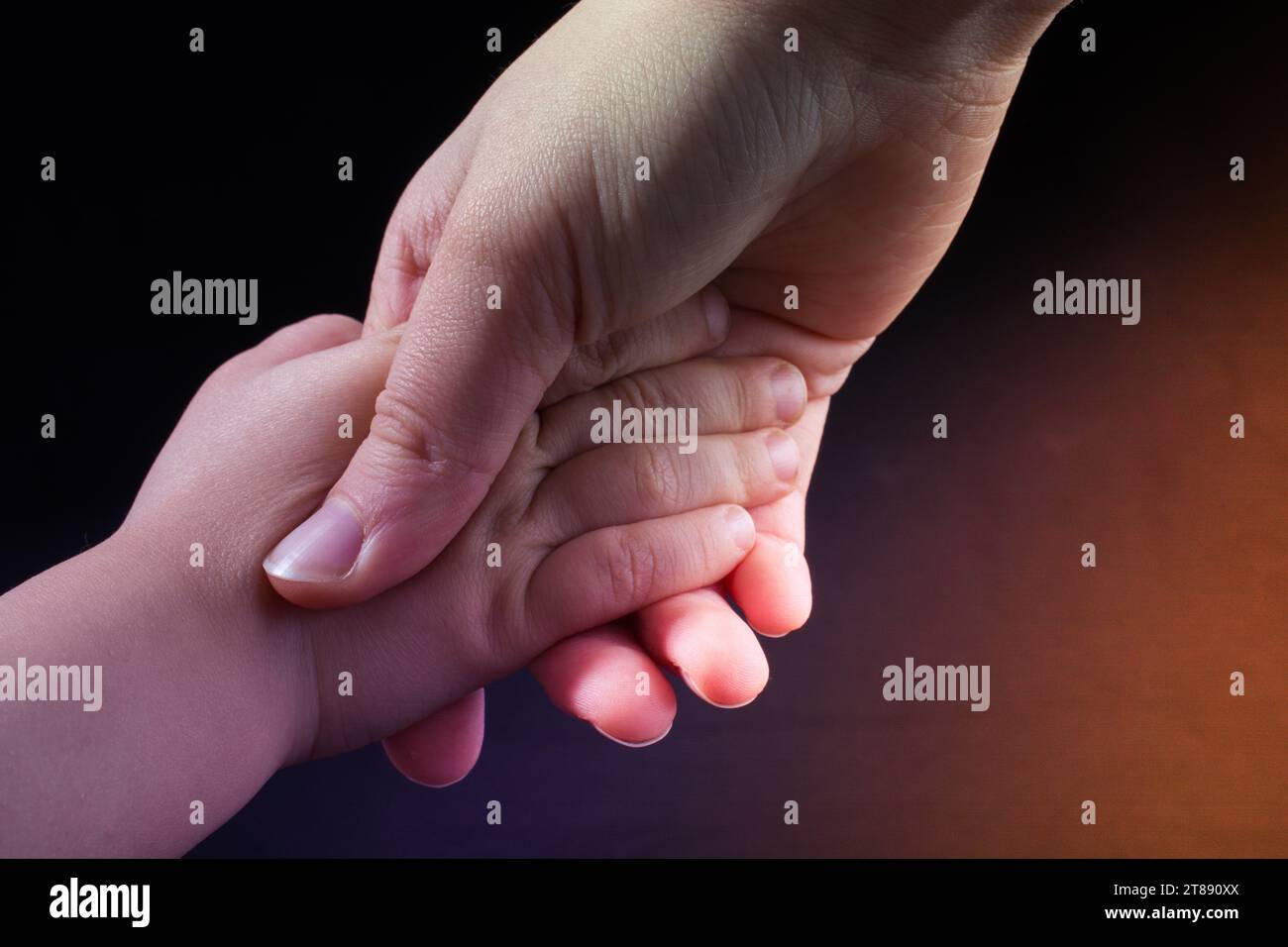 Adult and child hold hands in black background Stock Photo - Alamy