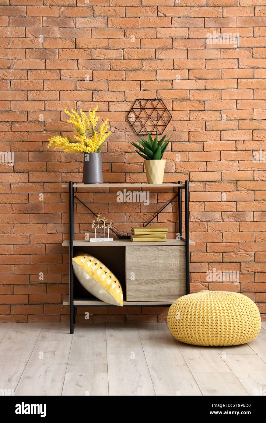 Shelving unit with different houseplants and books near brown brick ...