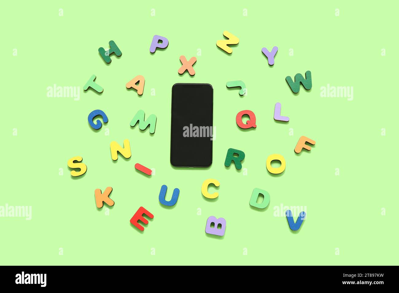 Mobile phone with blank screen and scattered letters on green ...