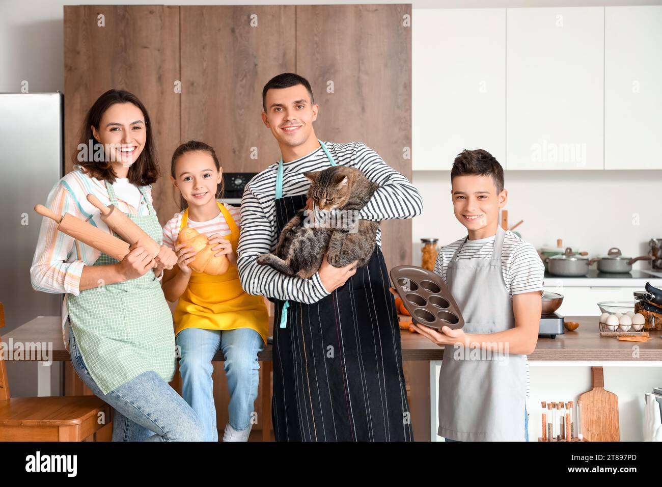 Happy family with cooking utensils and cat in kitchen Stock Photo - Alamy