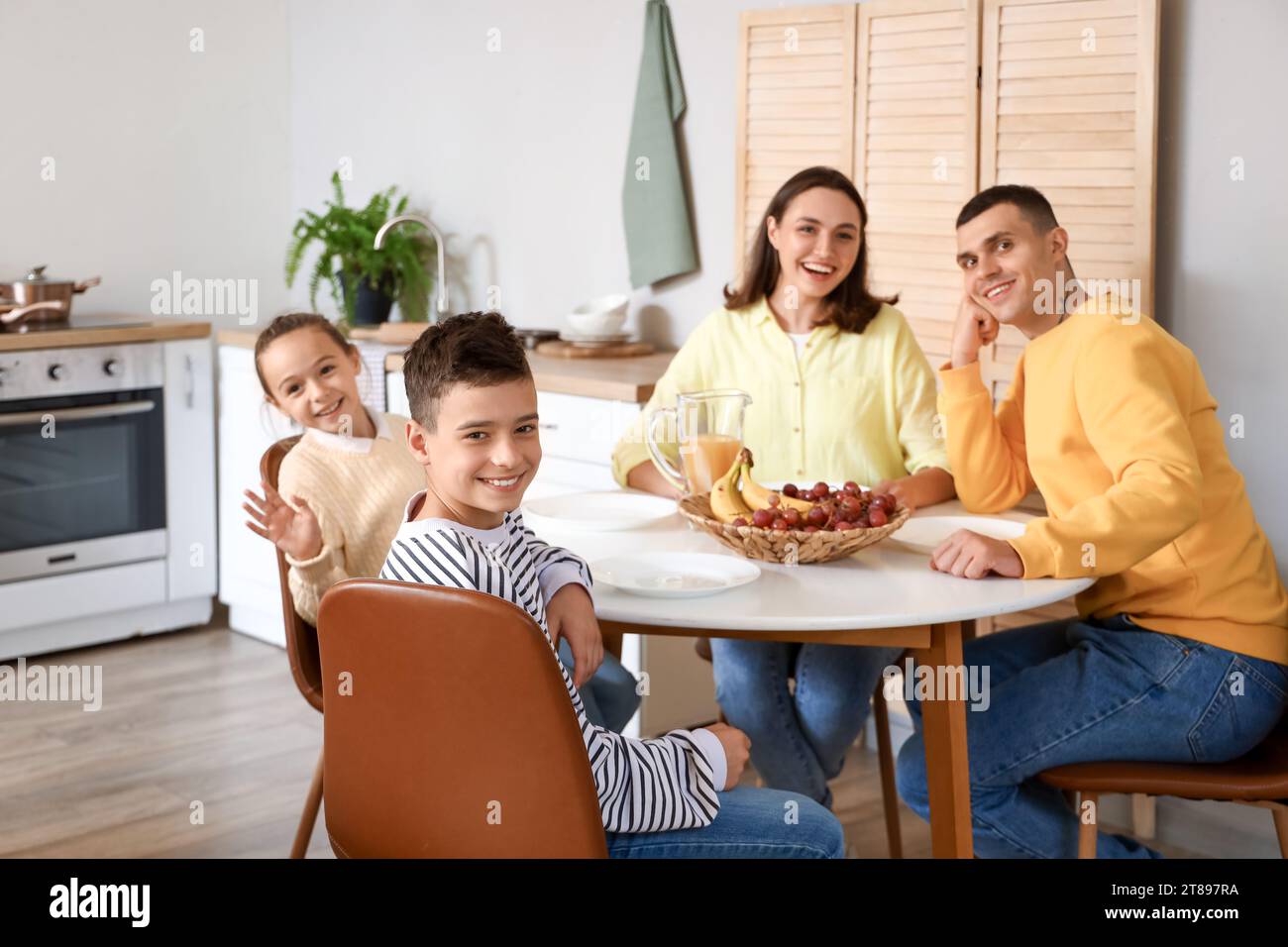Happy family sitting at dining table in kitchen Stock Photo - Alamy