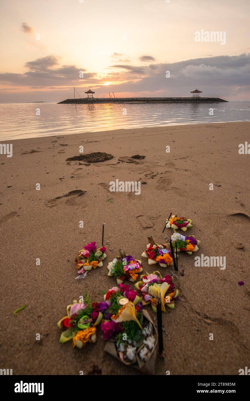Sunrise at the sandy beach of Sanur. Temple in the water. Offerings by ...
