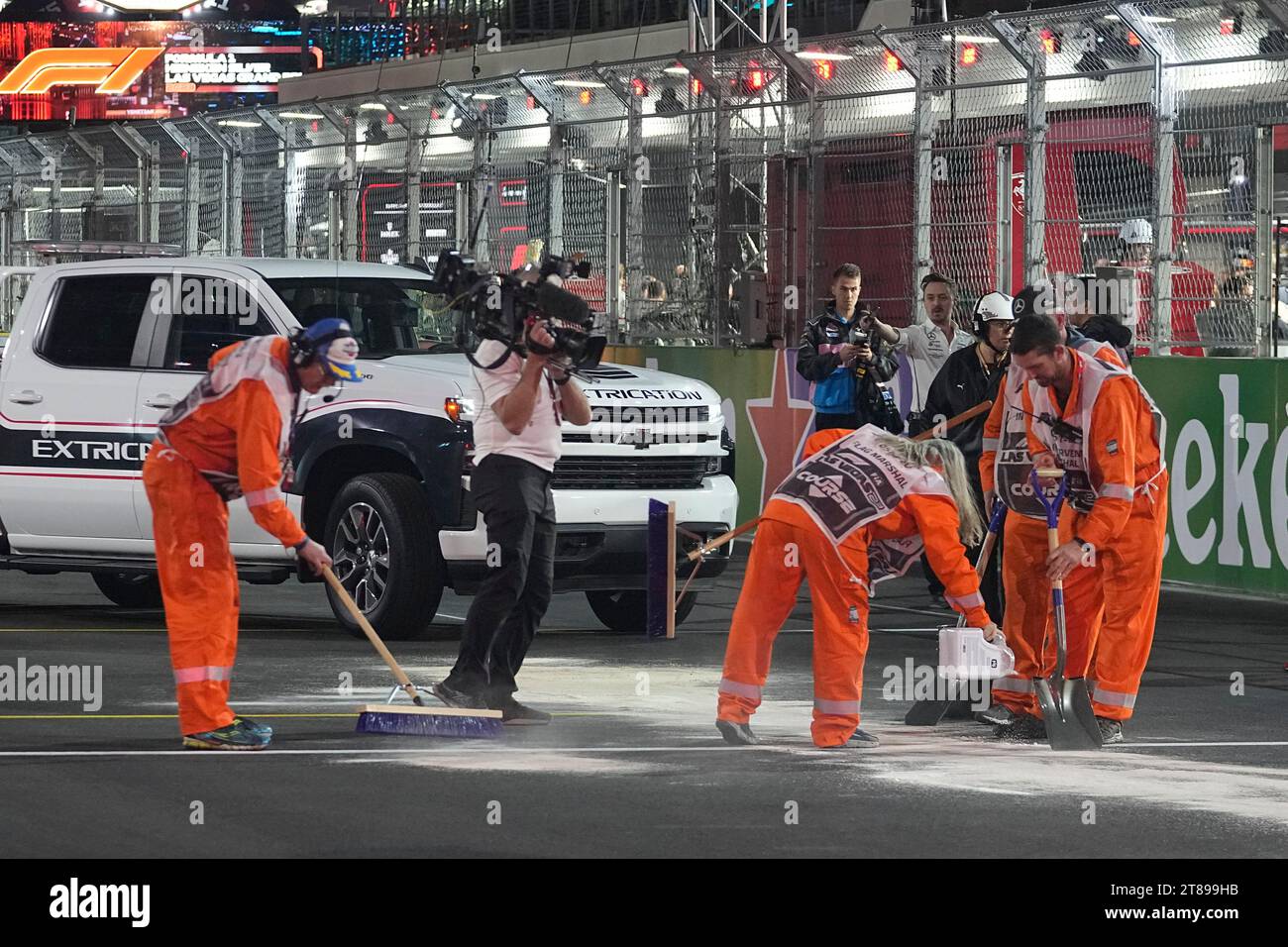 Workers clean up debris and liquid left by the pace cars during the ...