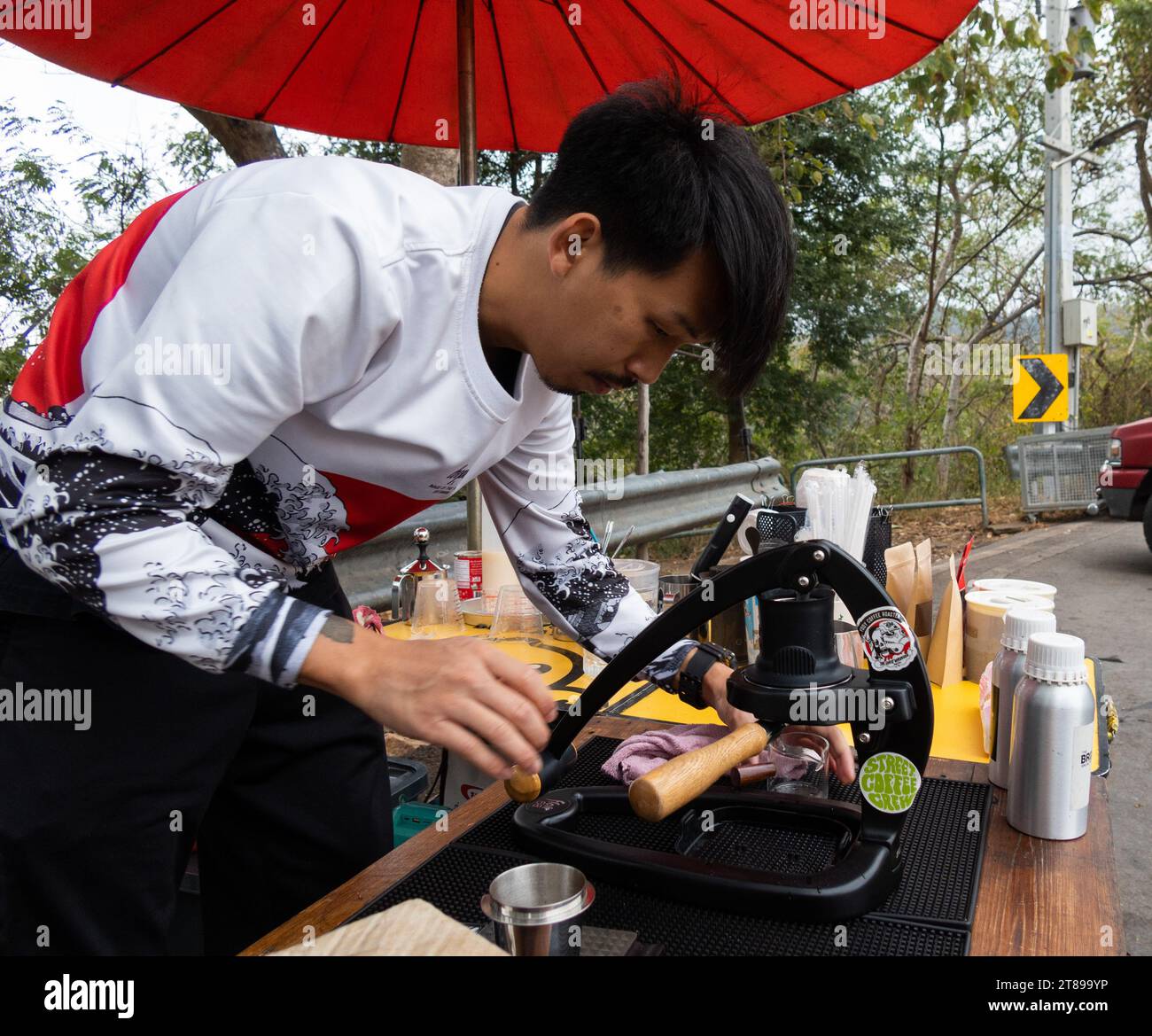 Thai roadside barista pulls an espresso shot using a portable lever ...