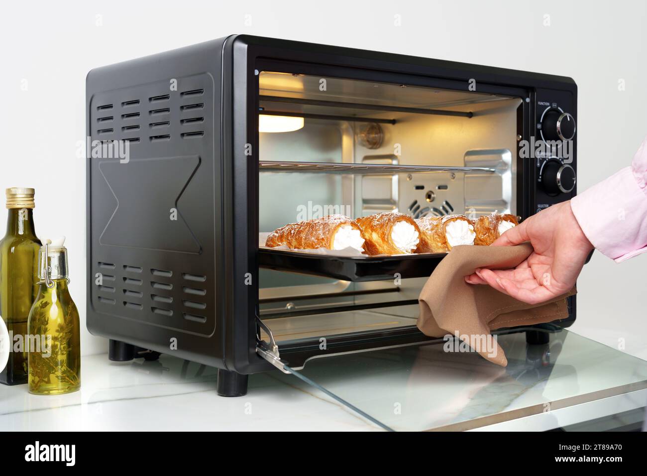 Woman's hands taking fresh bakery out of mini oven Stock Photo - Alamy