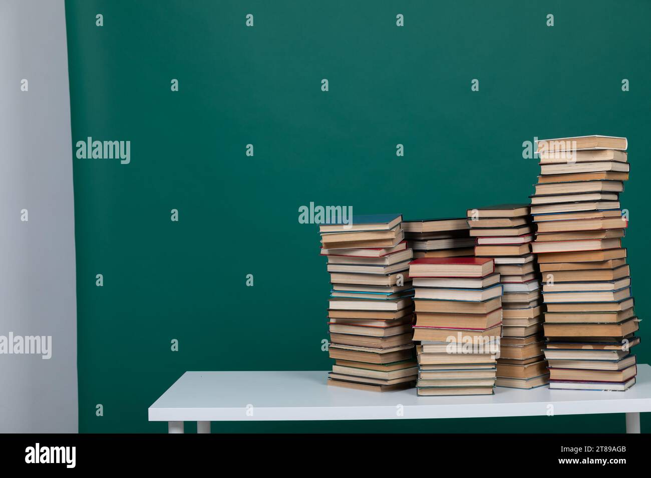 many books stacked on a table on a green background in the science ...