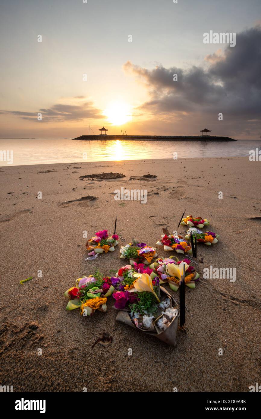 Sunrise at the sandy beach of Sanur. Temple in the water. Offerings by ...