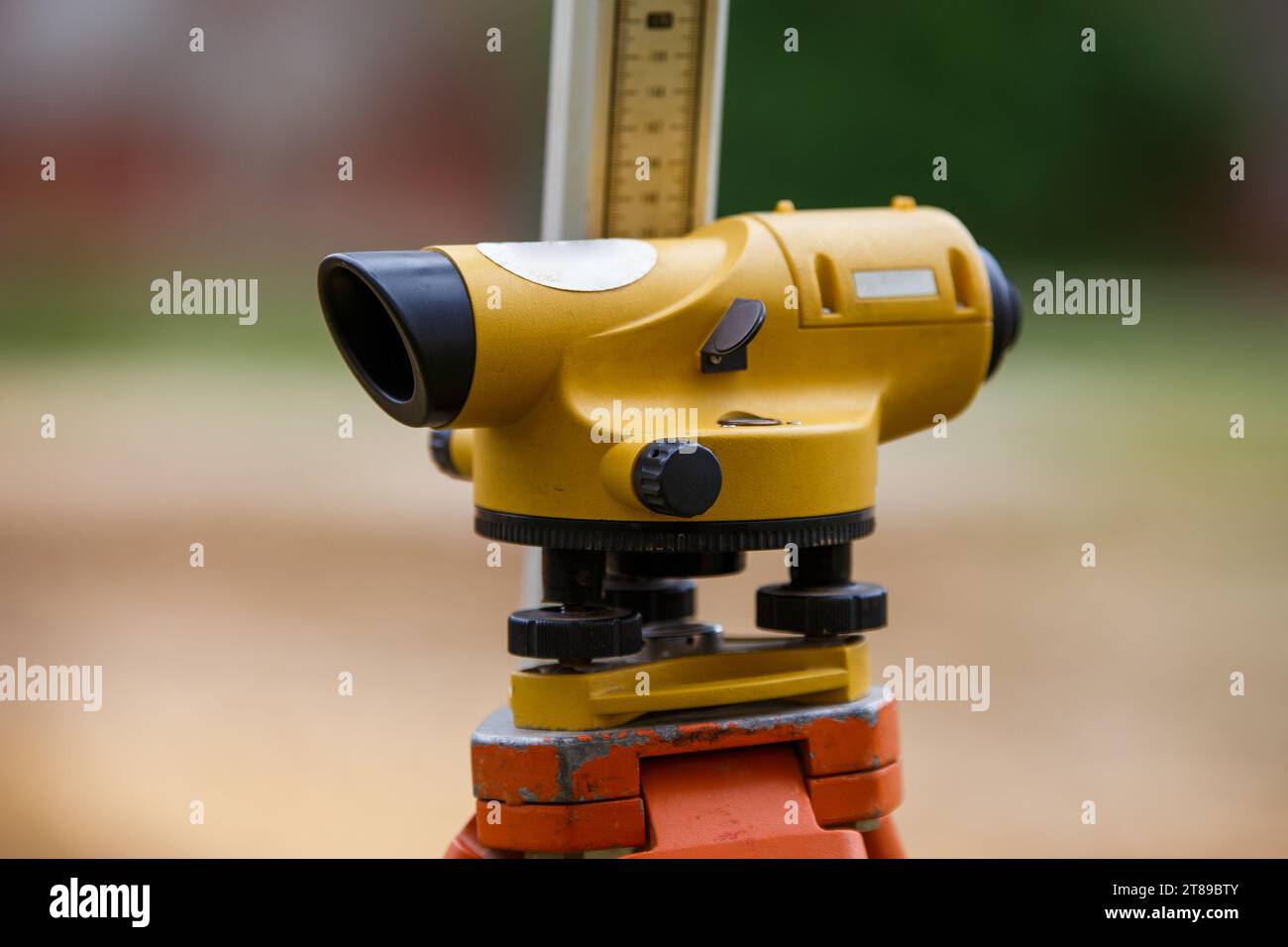 Yellow theodolite on a tripod and a ruler with a blurred background ...