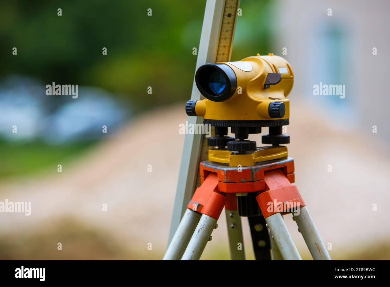Yellow theodolite on a tripod and a ruler with a blurred background ...