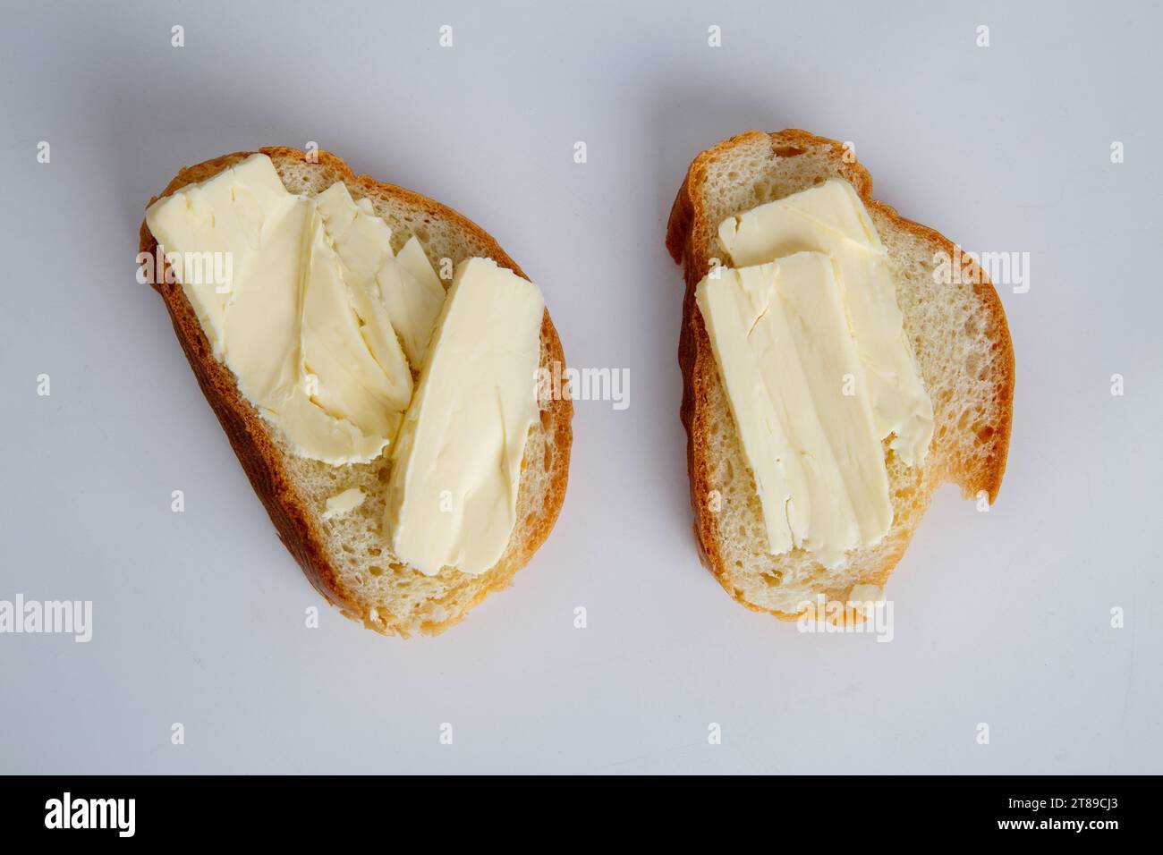 two pieces of white bread with butter on white background Stock Photo ...