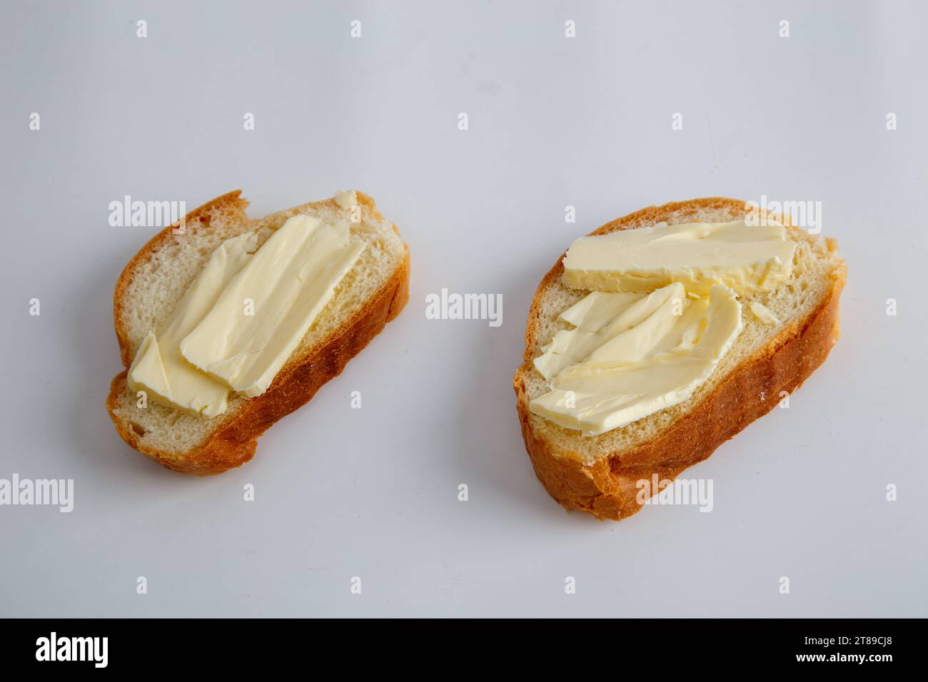 two pieces of white bread with butter on white background Stock Photo ...