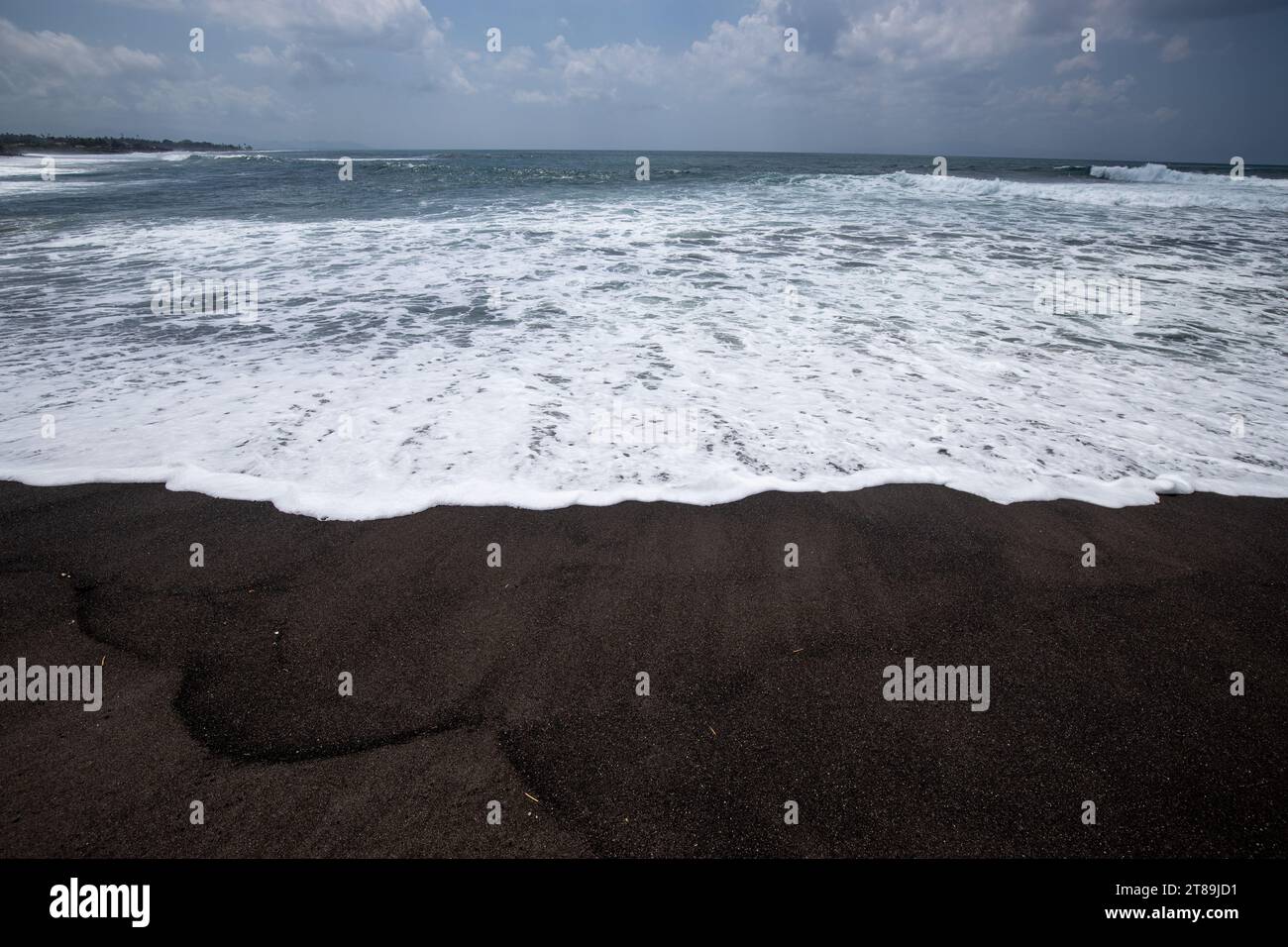 Black sand beach in Bali, with white waves and spray. lava sand beach ...