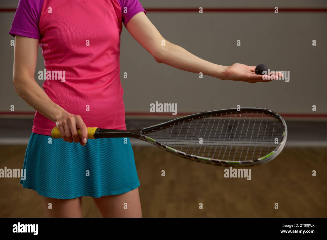 Closeup cropped view on female squash player holding racket and ball ...