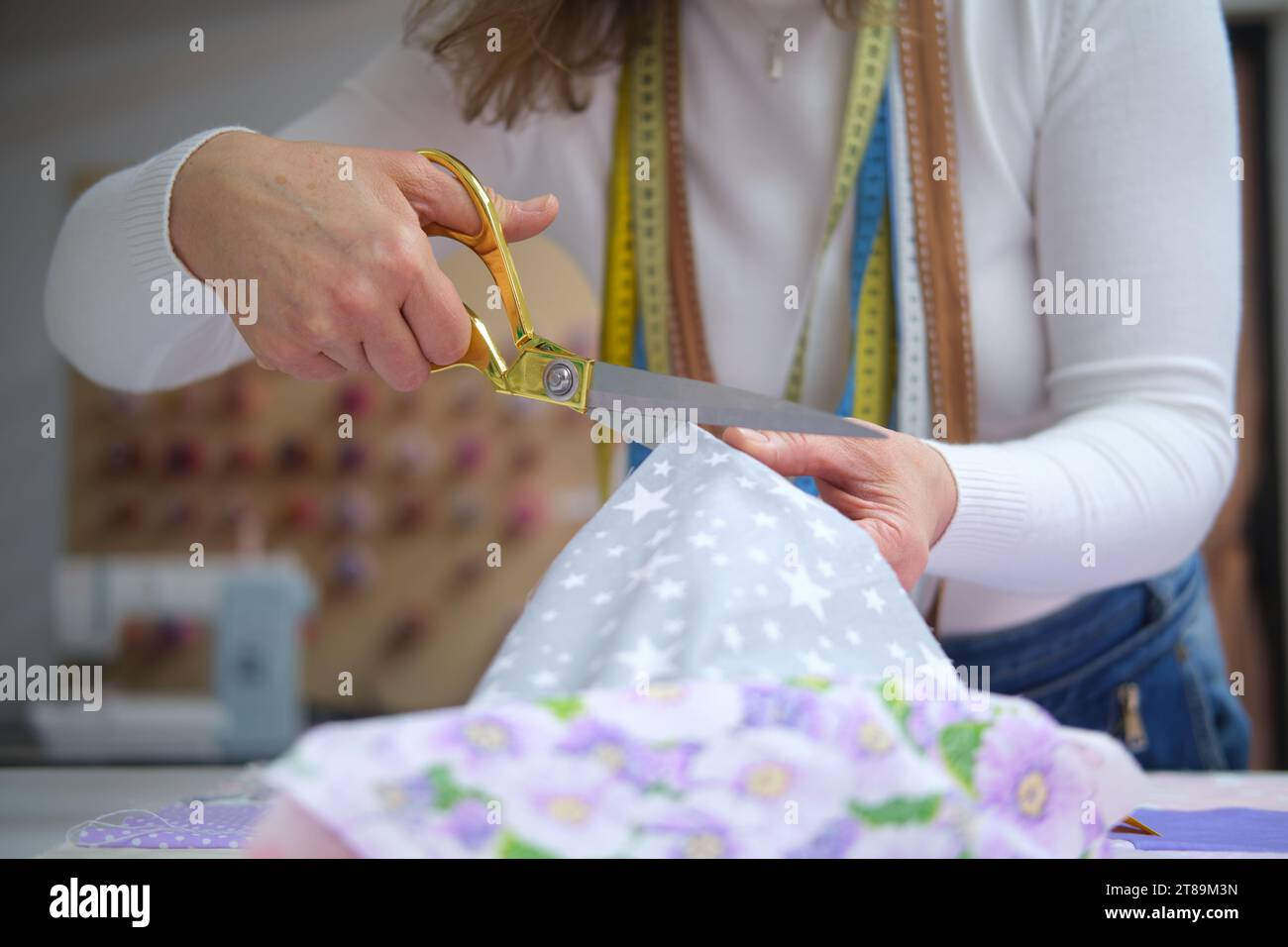 Close-up of a seamstress hands cutting cloth with scissors in the ...