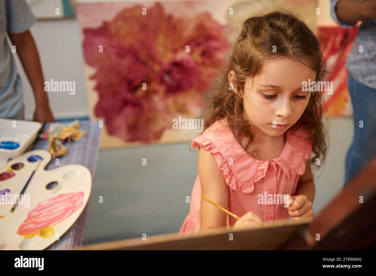 Talented elementary age kid girl, inspired artist painter enjoying her creative hobby indoors ...