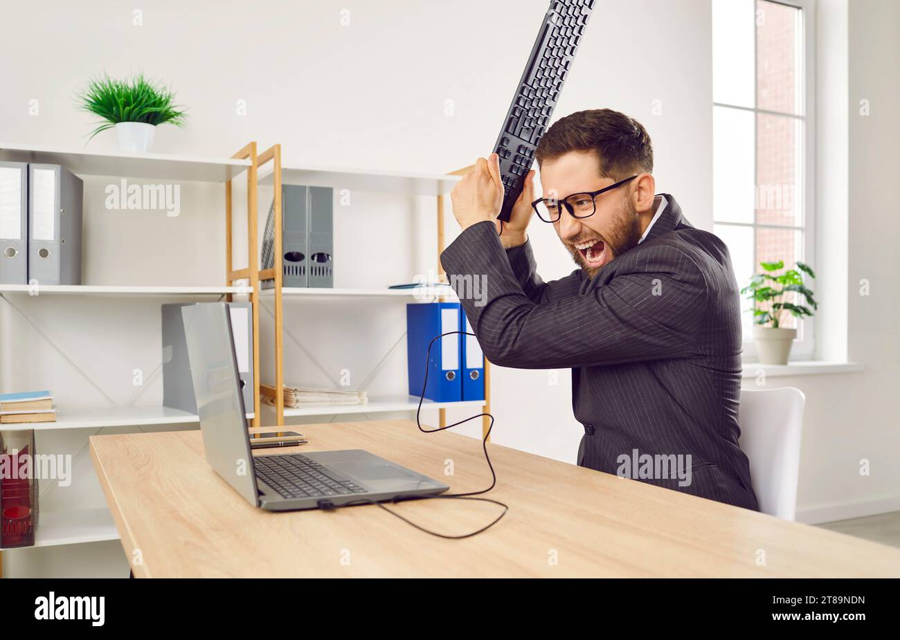 Angry shouting man working on workplace in office trying to destroy the ...