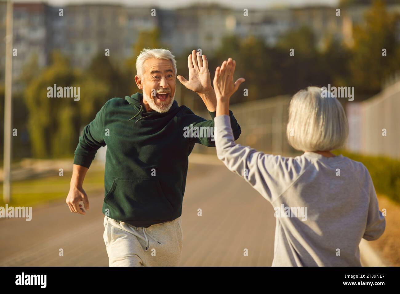 Two happy senior people have fun and high five each other after outdoor ...