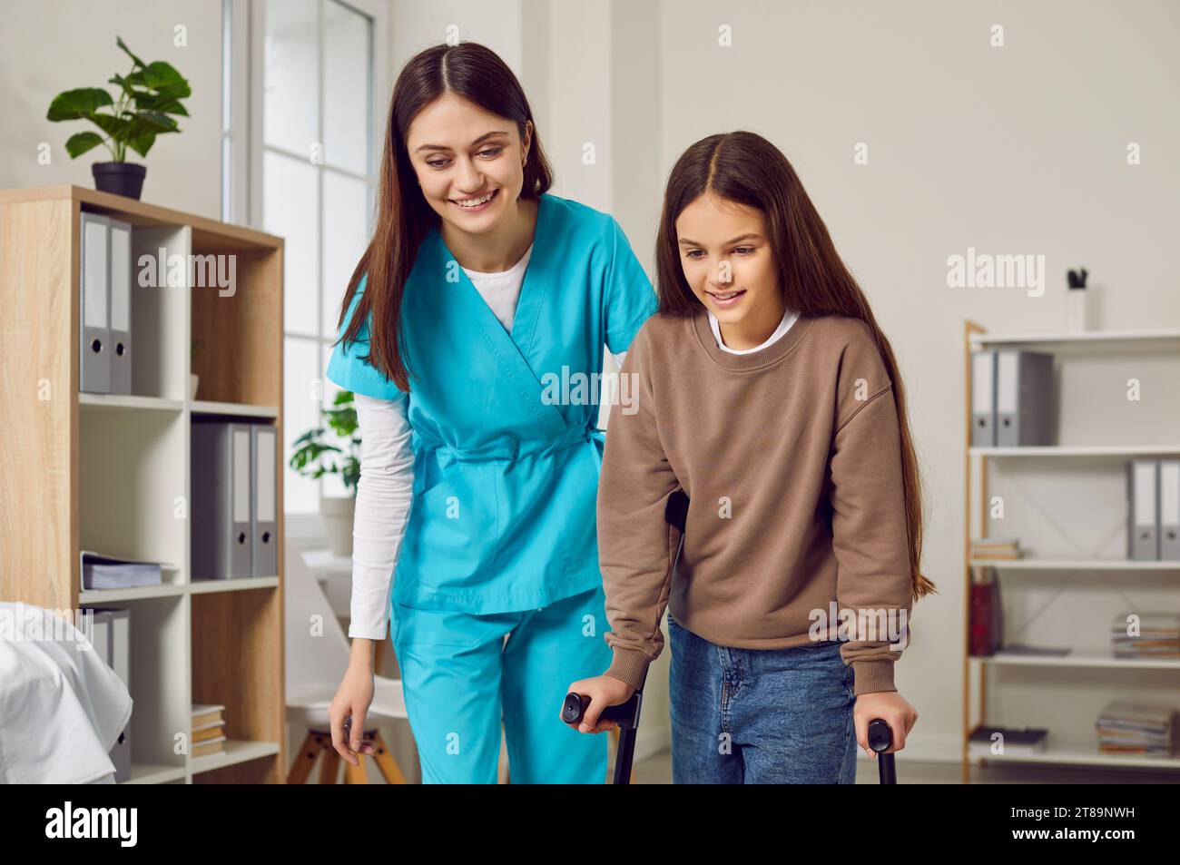 Young friendly nurse helping a child girl patient to walk with her ...