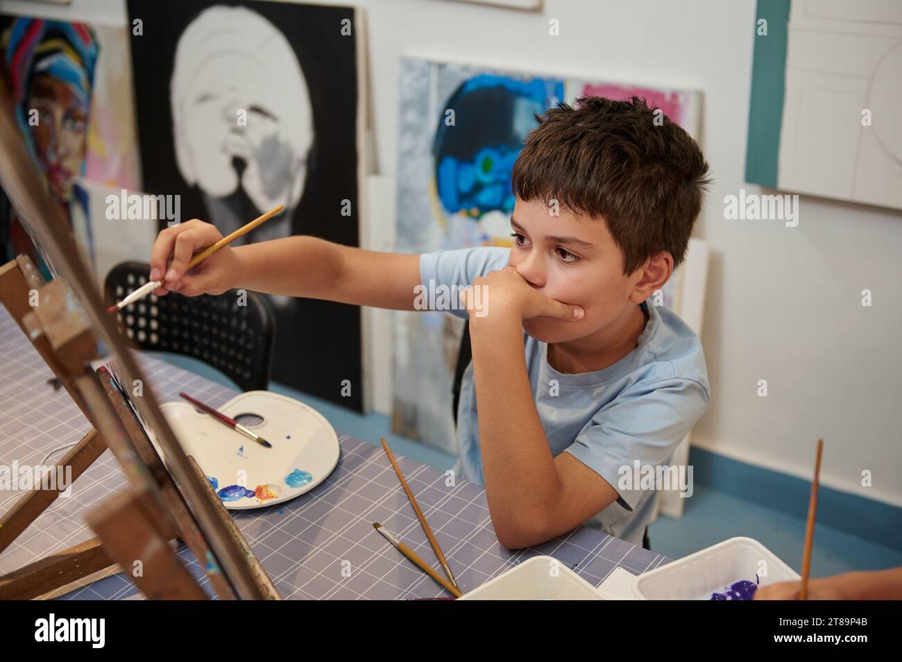 Handsome teen boy expressing himself while drawing on canvas, holding ...
