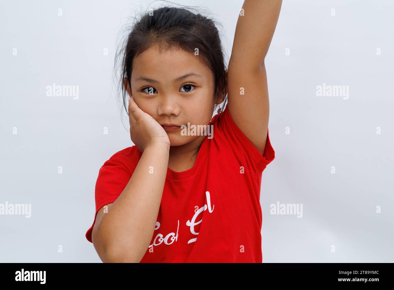 An Asian little girl raises her left hand straight up trying to ask ...