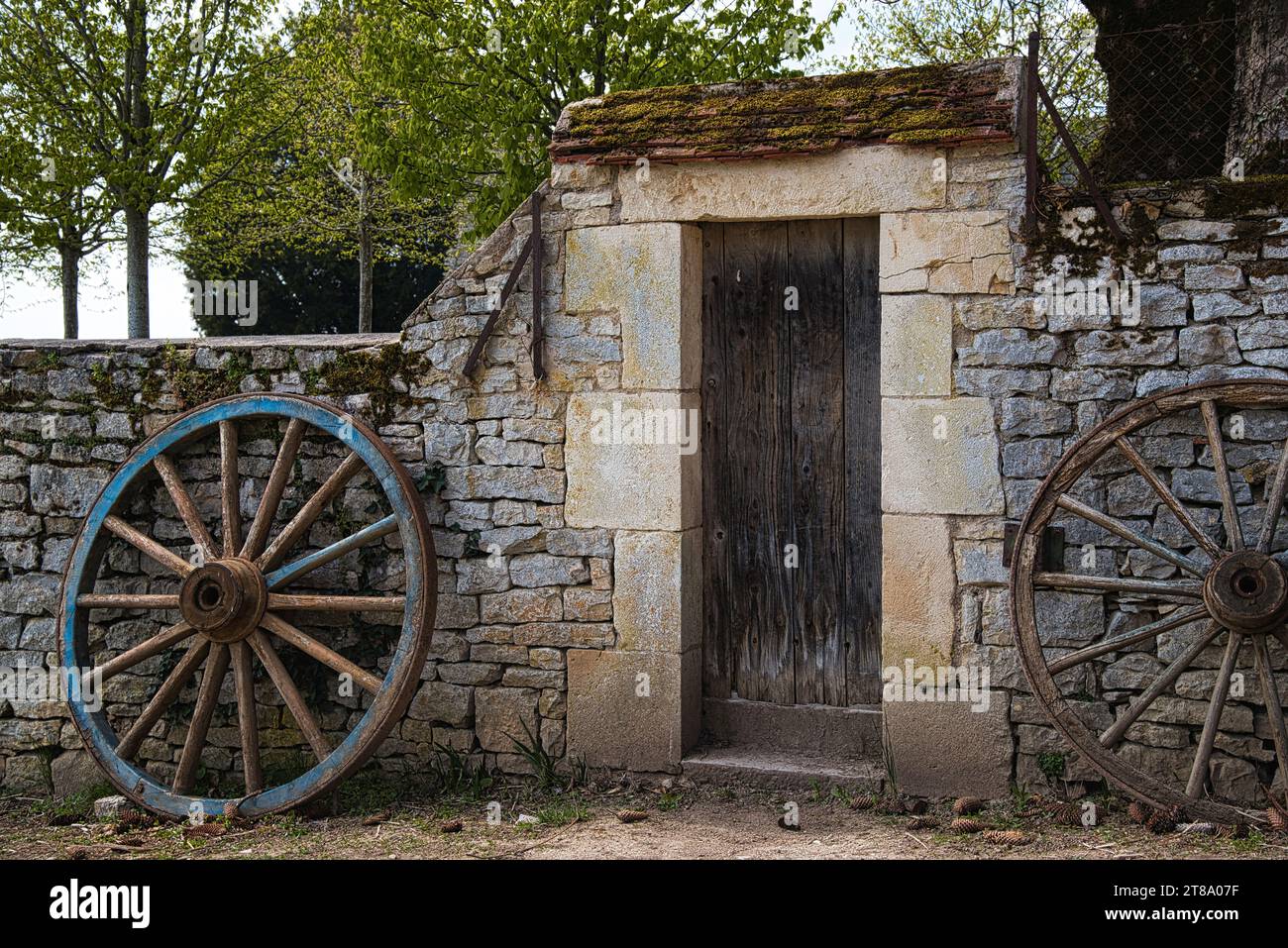 une roue de charrette appuyée sur un mur en pierre / a cartwheel ...