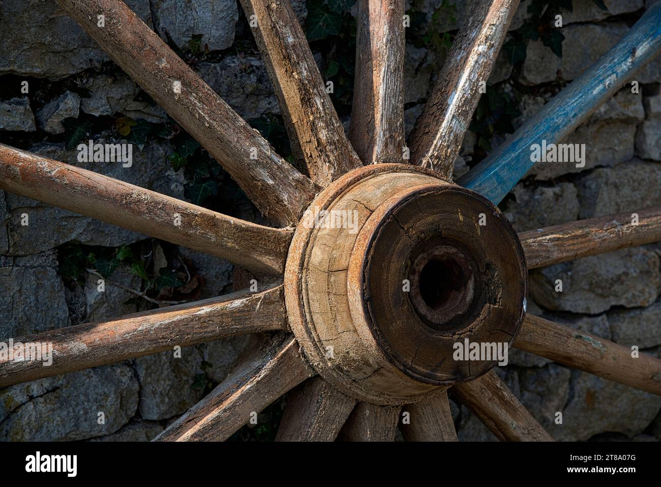 une roue de charrette appuyée sur un mur en pierre / a cartwheel ...