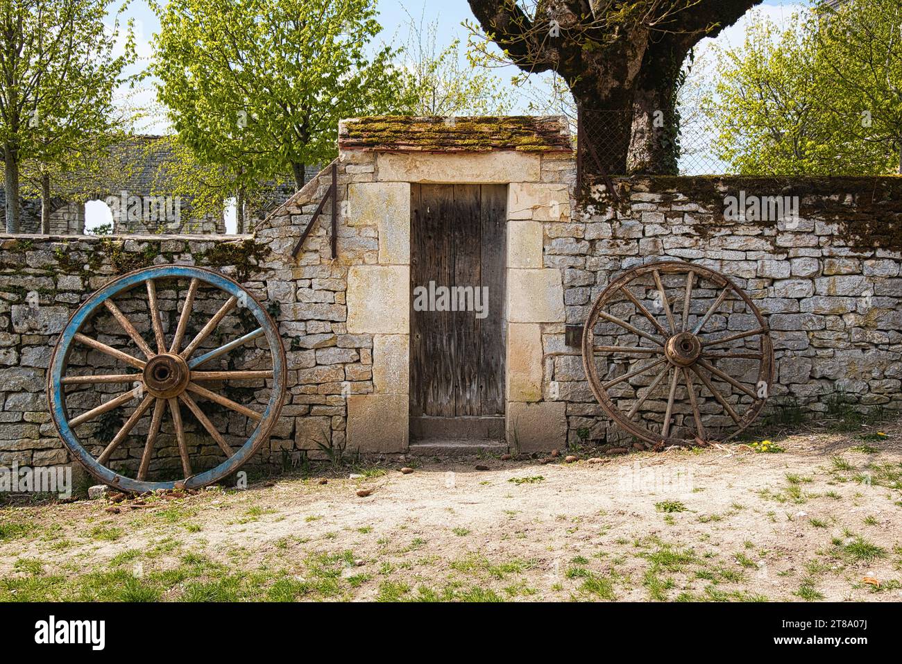 une roue de charrette appuyée sur un mur en pierre / a cartwheel ...